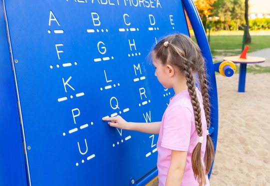 A little girl is studying Morse code on a blackboard in the playground ...